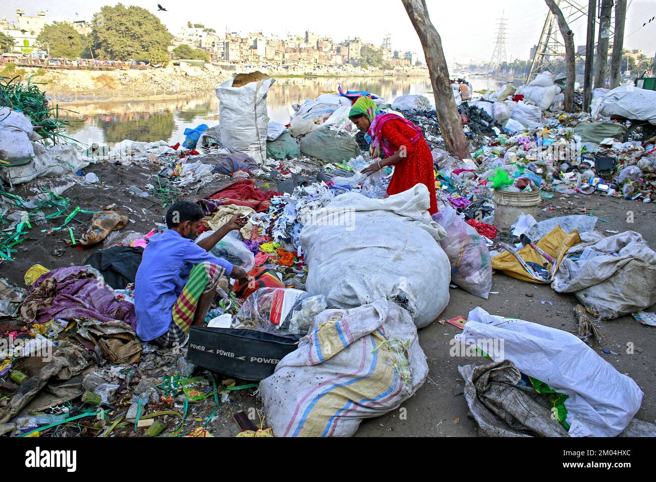 A Bangladeshi woman looks for plastic object from a garbage dump on the ...