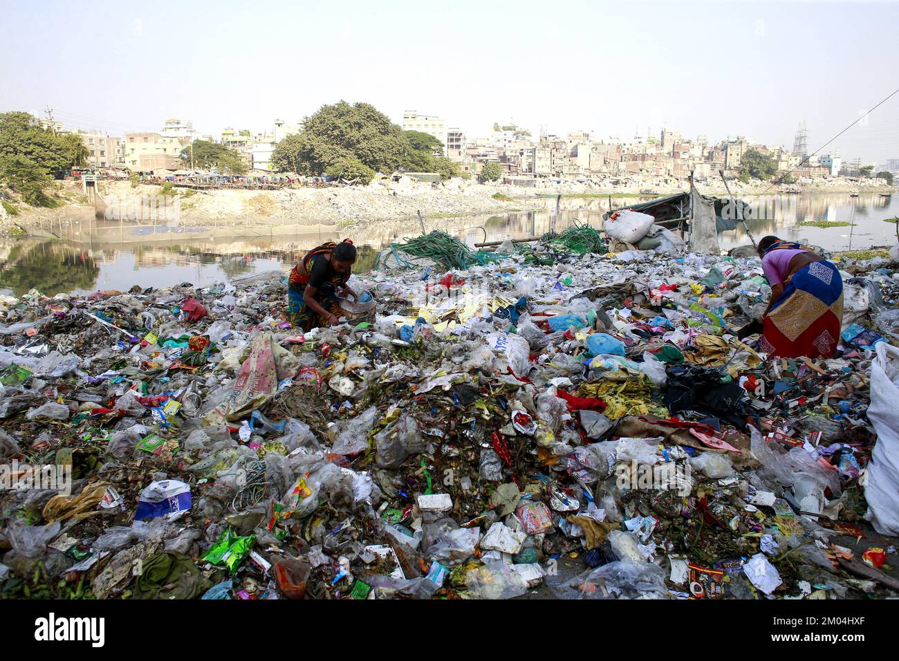 A Bangladeshi woman looks for plastic object from a garbage dump on the ...