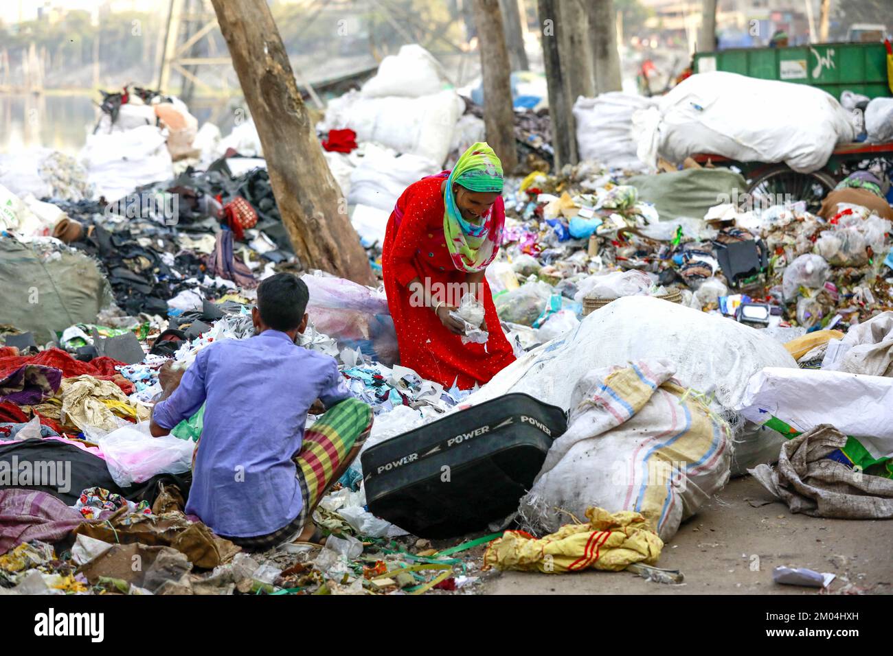 A Bangladeshi woman looks for plastic object from a garbage dump on the ...