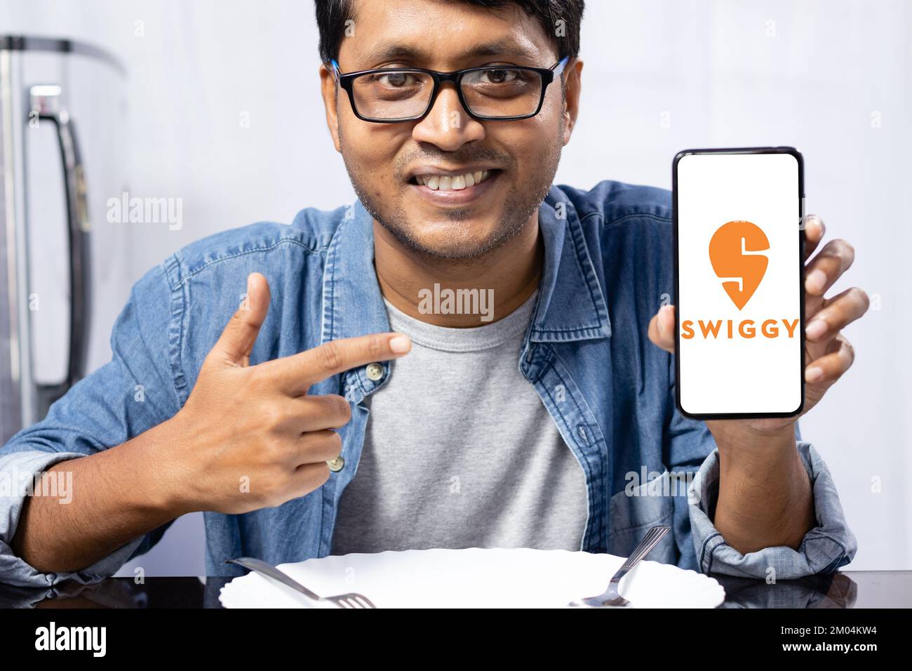 Close up of an Indian ethnicity male pointing at swiggy food delivery ...