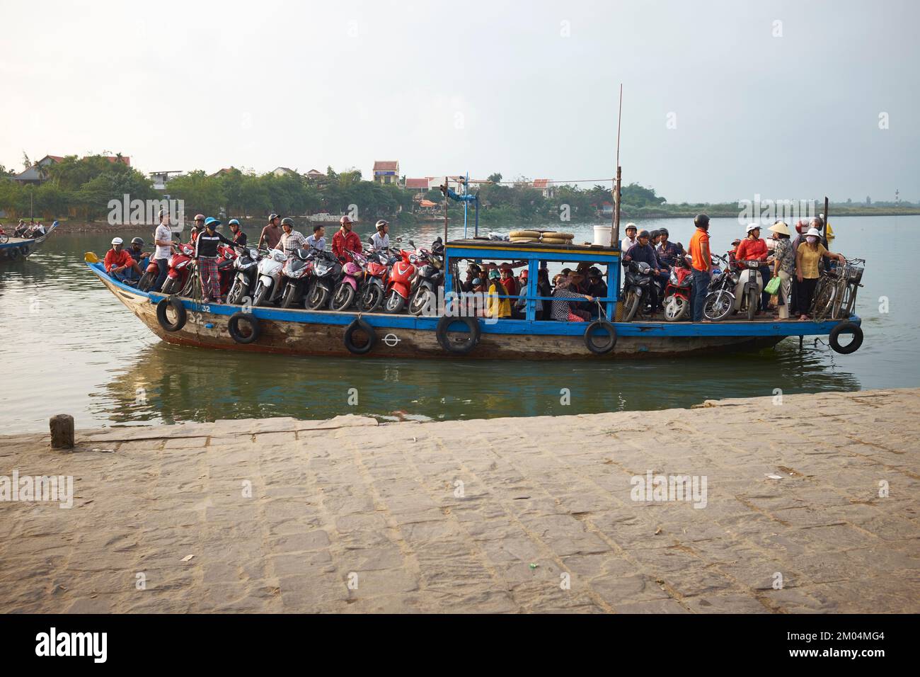 Cross river ferry arriving with boatload of passengers in in Hoi An ...