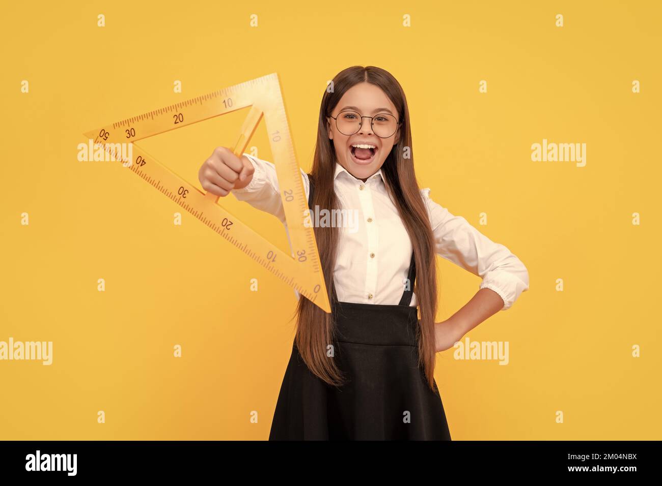 happy teen girl in school uniform and glasses hold mathematics triangle ...