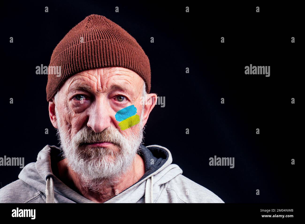 poor caucasian old men with Ukraine flag painted on cheek in studio ...