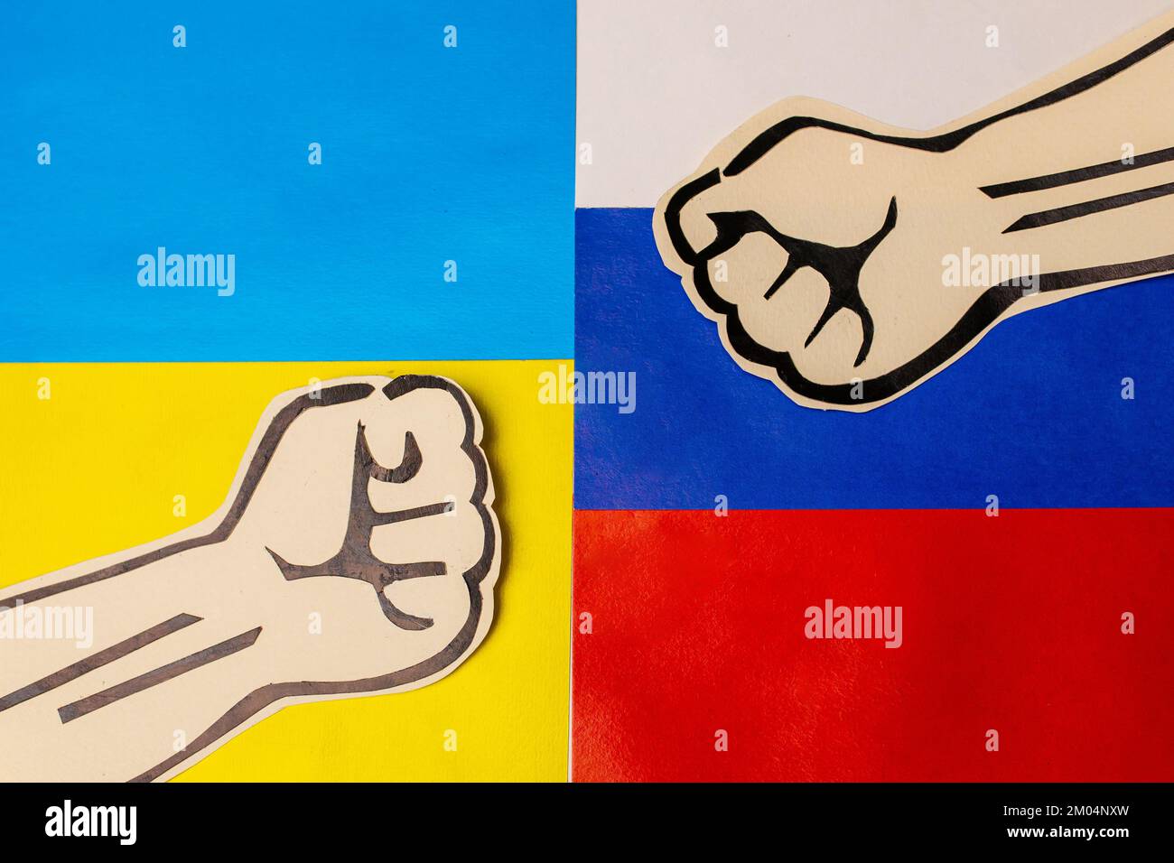 two cardboard fists on flags of Russia and Ukraine. Russian versus ...