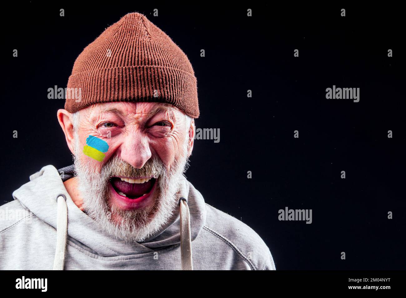 poor caucasian old men with Ukraine flag painted on cheek in studio ...
