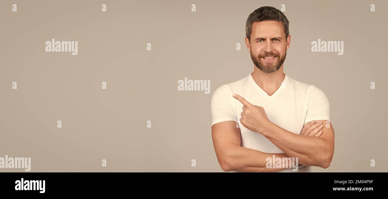 Happy handsome man smile pointing finger aside at grey background copy space, advertise. Man ...