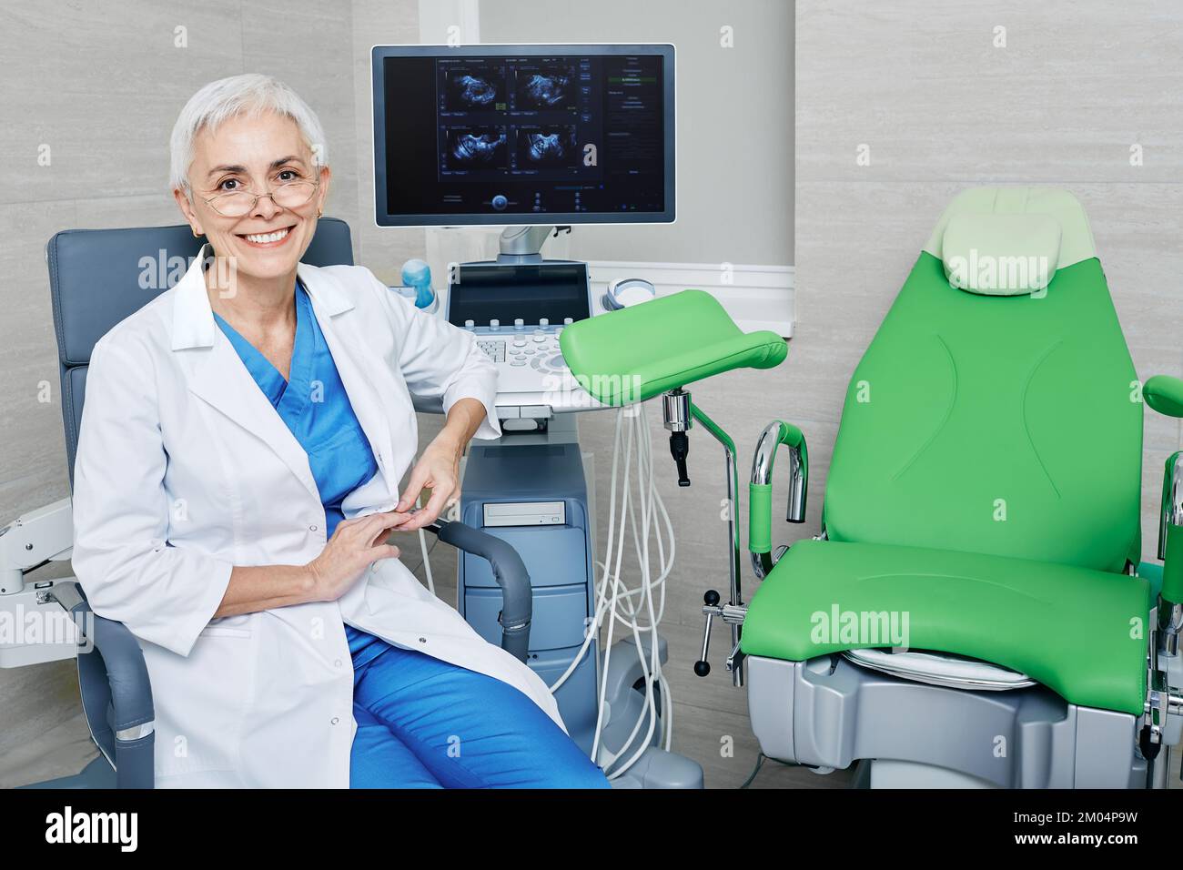 Portrait of gynecologist sitting near gynecological chair and ...