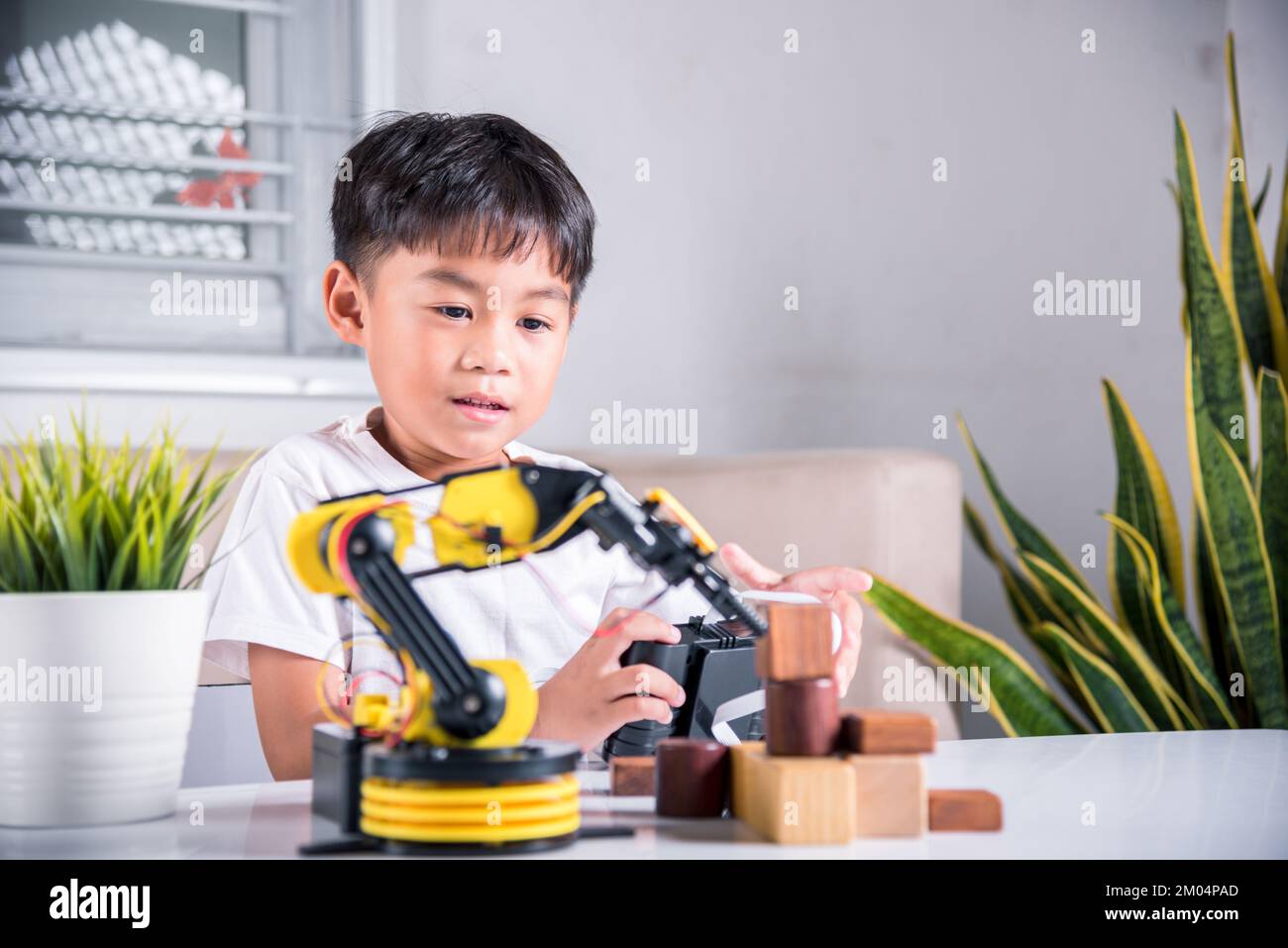 Happy Asian little kid boy using remote control playing robotic machine ...
