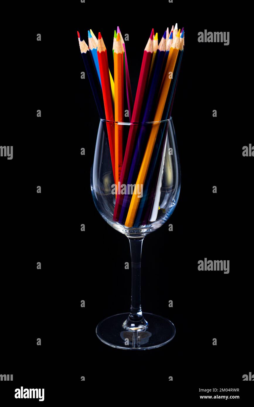 multi-colored pencils in a wine glass and a bucket. Selective blurred a ...