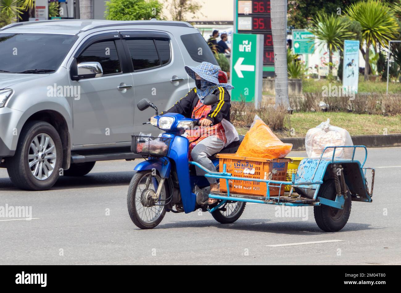 RATCHABURI, THAILAND, NOV 16 2022, A woman rides a motorcycle with a ...
