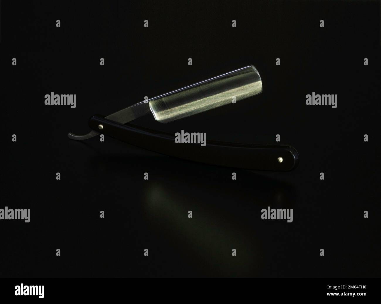 A straight razor with dark brown scales on black background Stock Photo ...