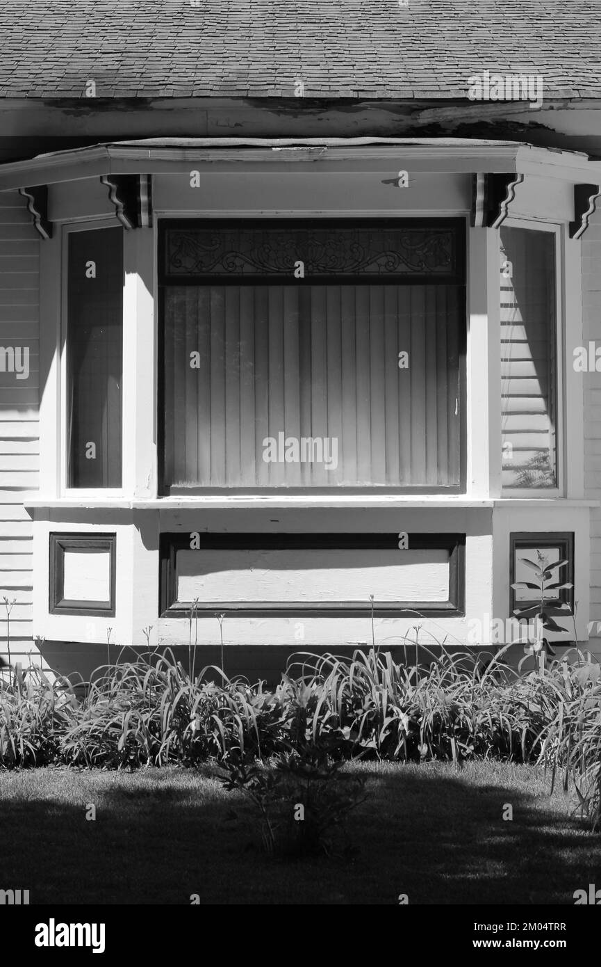 Traditional wooden cottage window on the wall of a house in a black and ...
