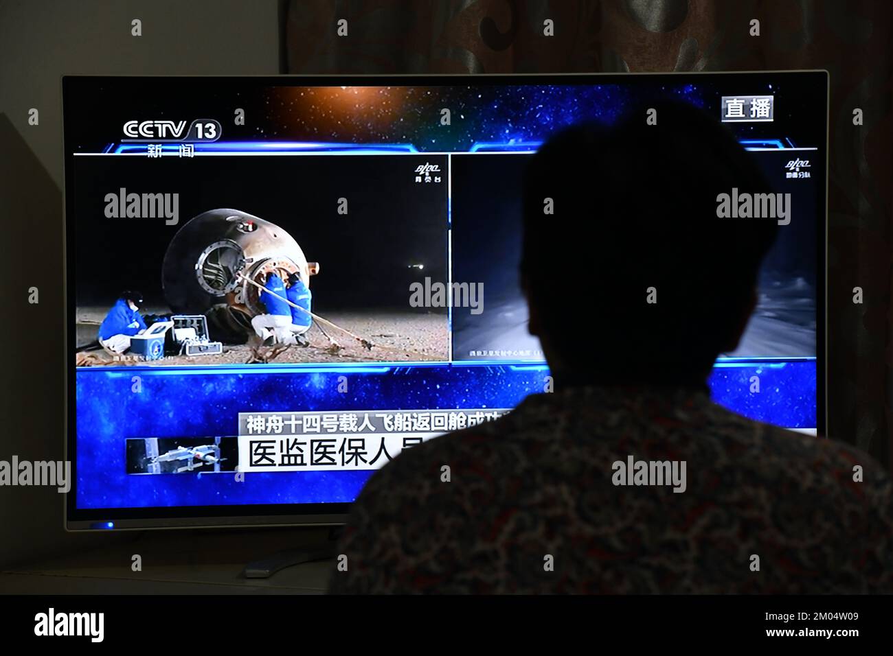 FUYANG, CHINA - DECEMBER 4, 2022 - Citizens watch a live TV broadcast of the re-entry module of ...