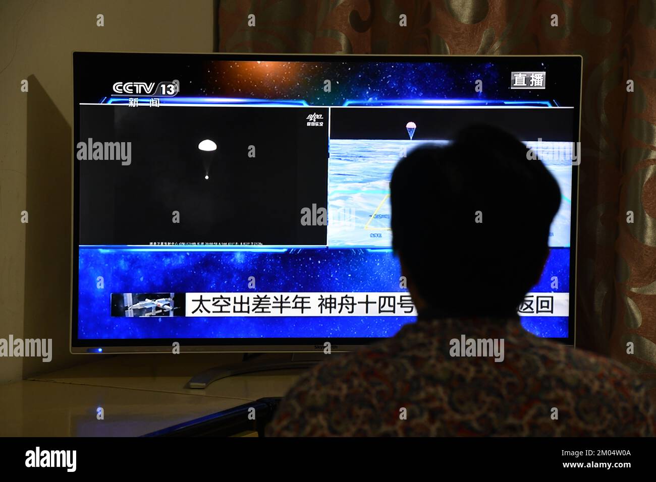 FUYANG, CHINA - DECEMBER 4, 2022 - Citizens watch a live TV broadcast of the re-entry module of ...