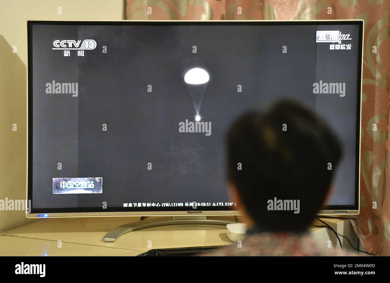 FUYANG, CHINA - DECEMBER 4, 2022 - Citizens watch a live TV broadcast of the re-entry module of ...