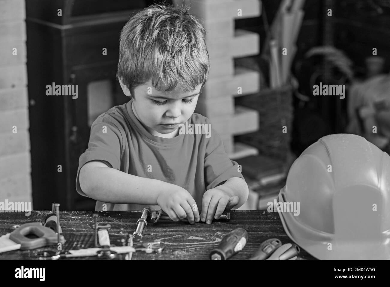 Kid fixing two metal details. Concentrated boy working with screw bolts ...
