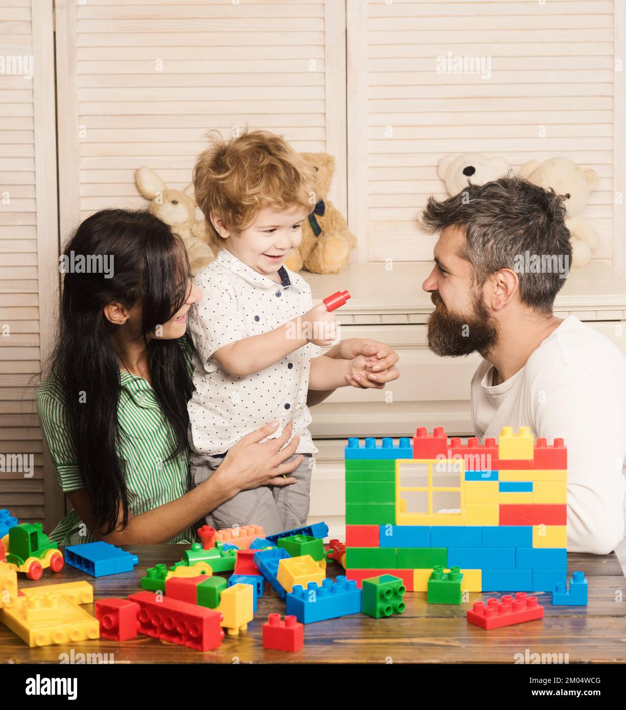 Father, mother and cute kid on light wooden background Stock Photo - Alamy