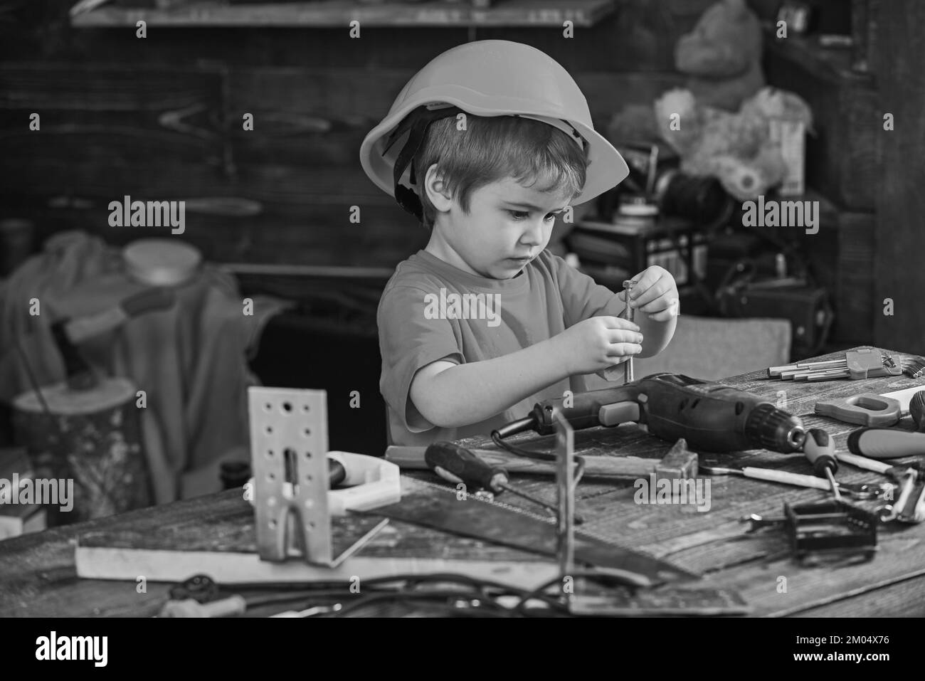 Small boy piling up big metal screw bolts. Side view cute kid playing ...