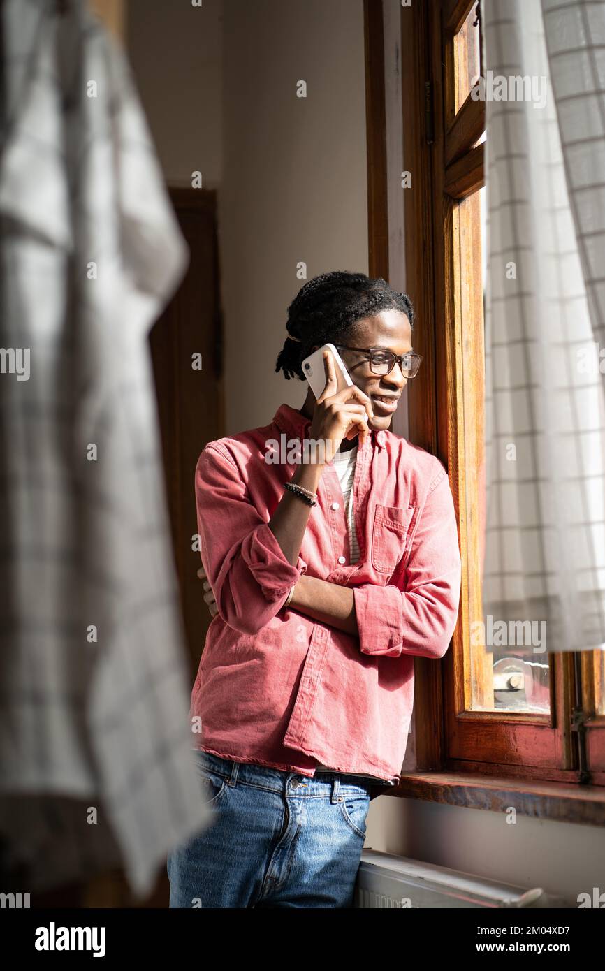 Smiling millennial African guy talking on phone with girlfriend ...