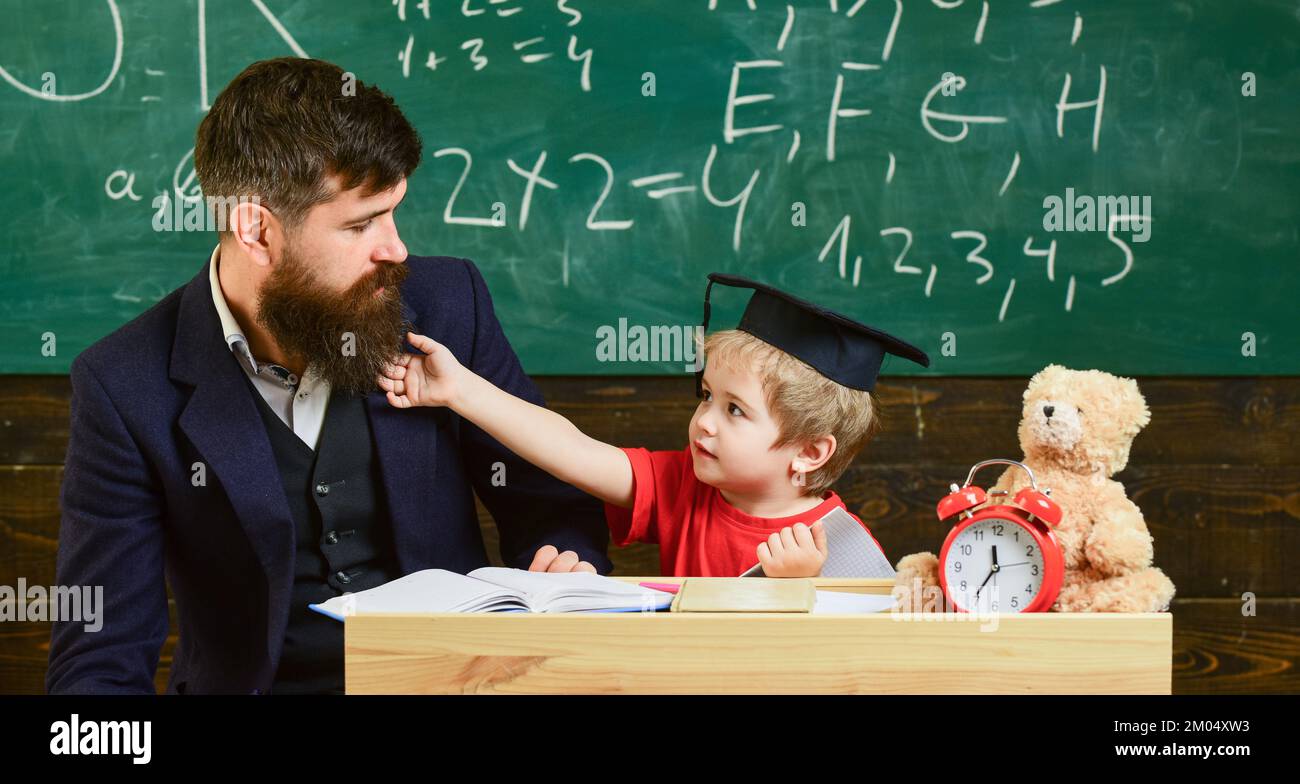 Teacher and pupil in mortarboard, chalkboard on background. Kid ...