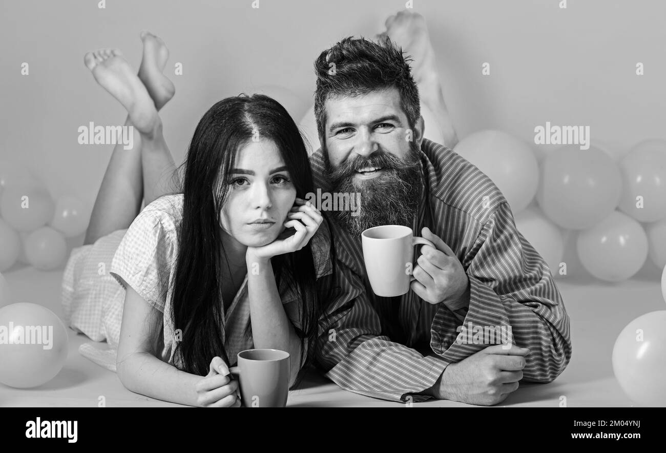 Couple relax in morning with coffee. Man and woman on smiling faces lay ...