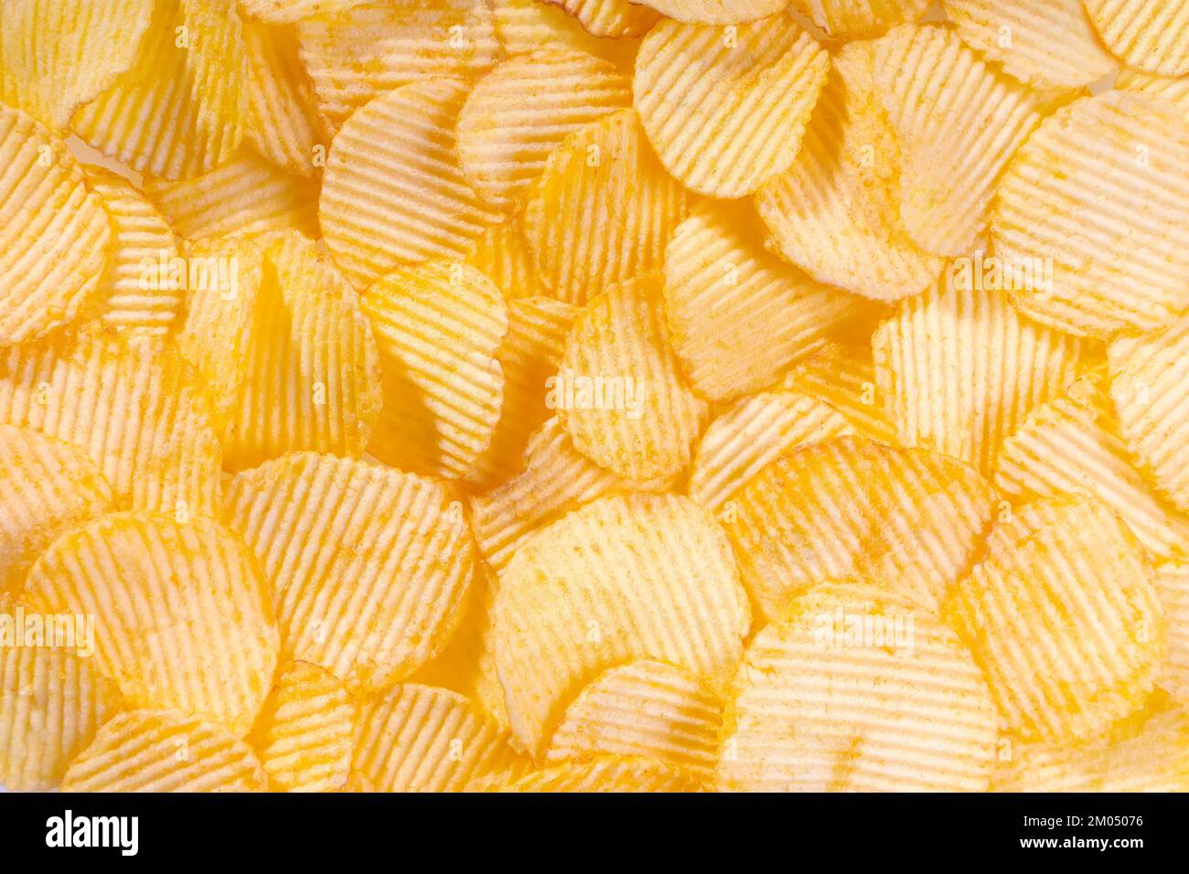 Yellow crispy ridged potato chips close up. Food background, banner ...