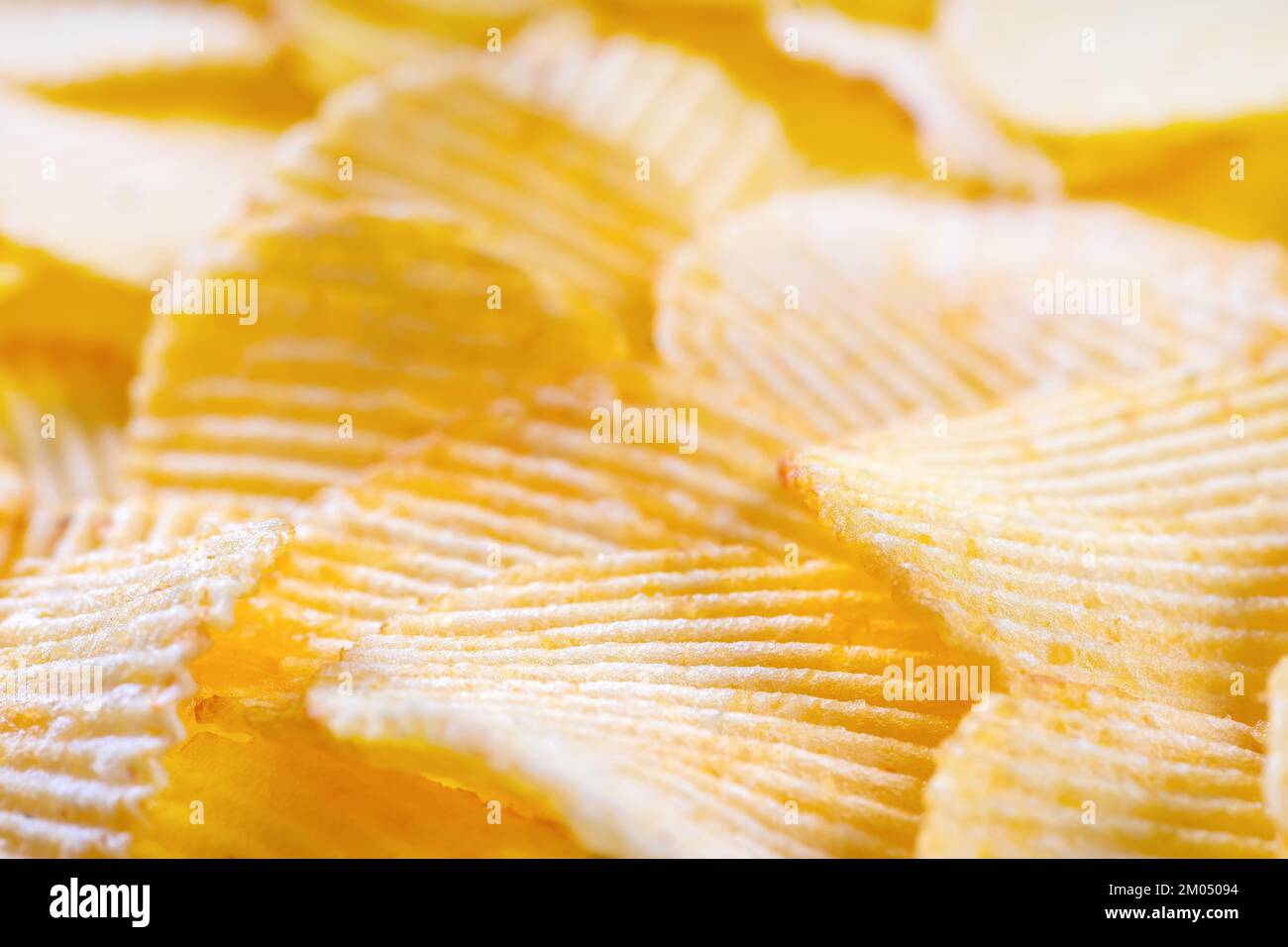 Yellow crispy ridged potato chips close up. Food background, banner ...
