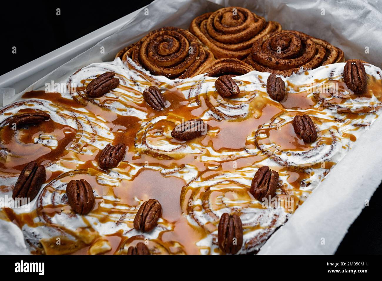 Cinnabon rolls with cinnamon, nougat, cream and nuts, on baking paper ...