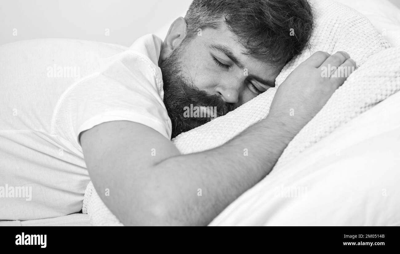 Man in shirt laying on bed, white wall on background. Macho with beard ...