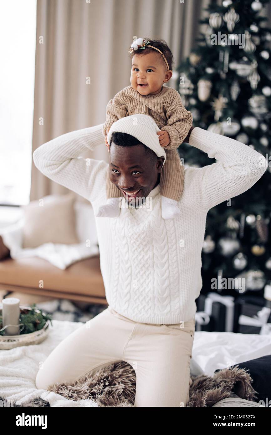 Happy african man plays with his mixed race baby daughter against ...