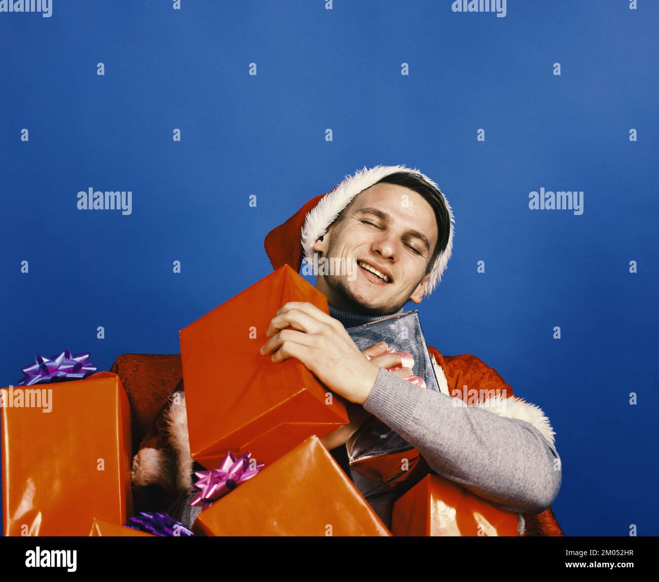 Guy with happy face holds many red and silver gifts Stock Photo - Alamy