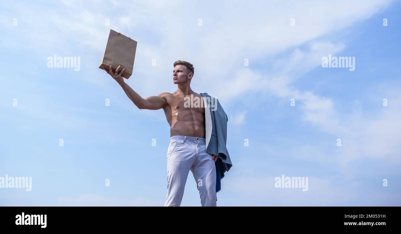 Man muscular athlete hold shopping bag sky background. Hot sales and ...