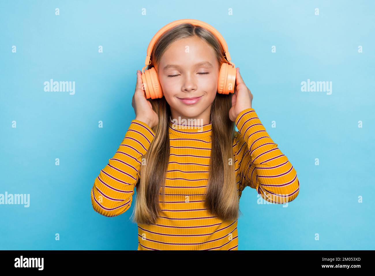Photo of peaceful cute girl closed eyed hands touch headphones listen ...