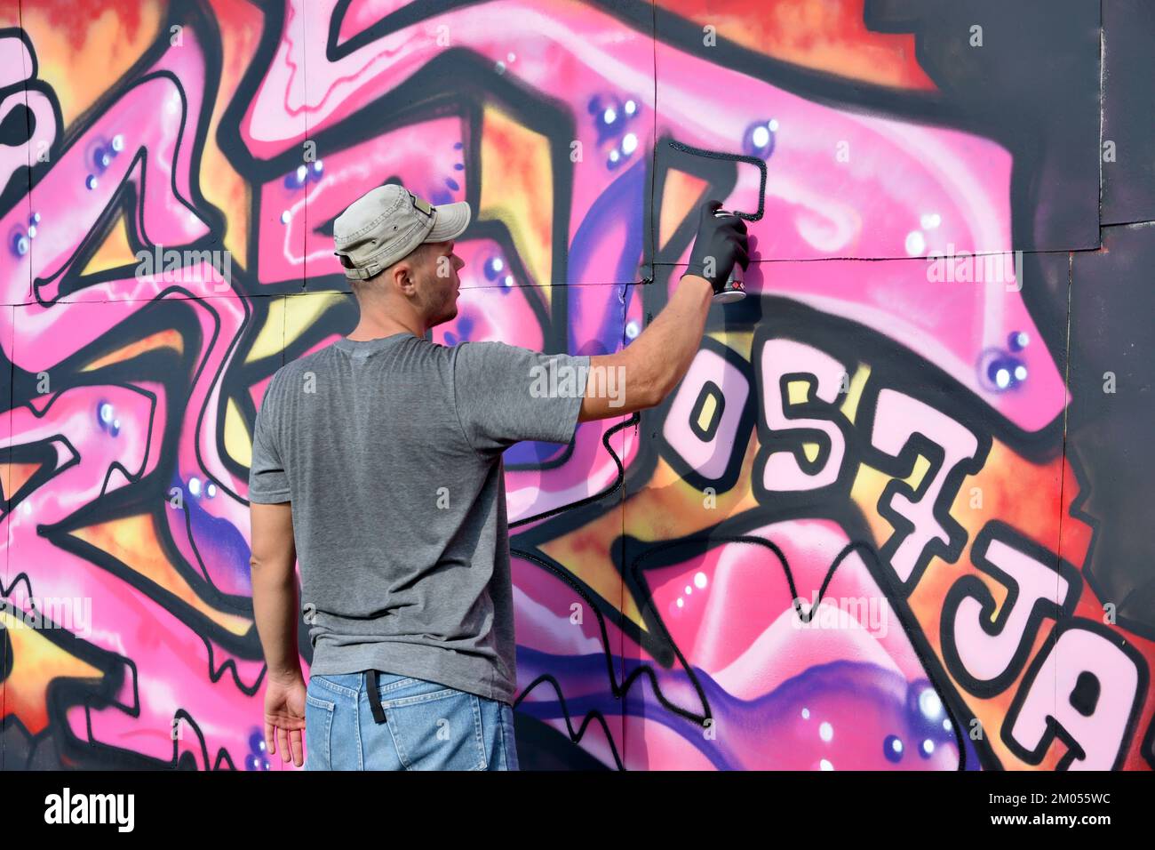 Young caucasian male graffiti artist drawing big street art painting in ...