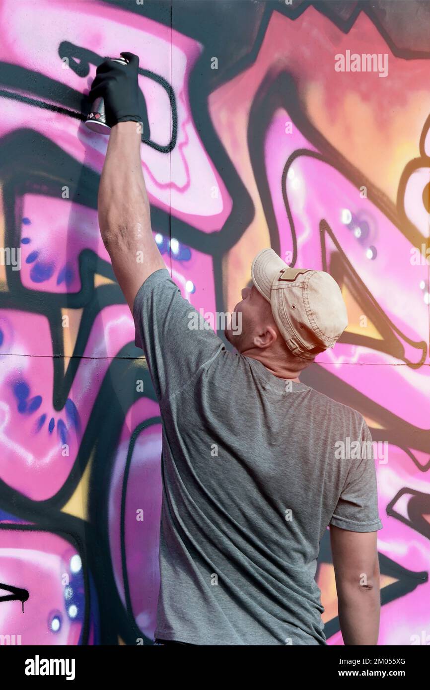 Young caucasian male graffiti artist drawing big street art painting in ...