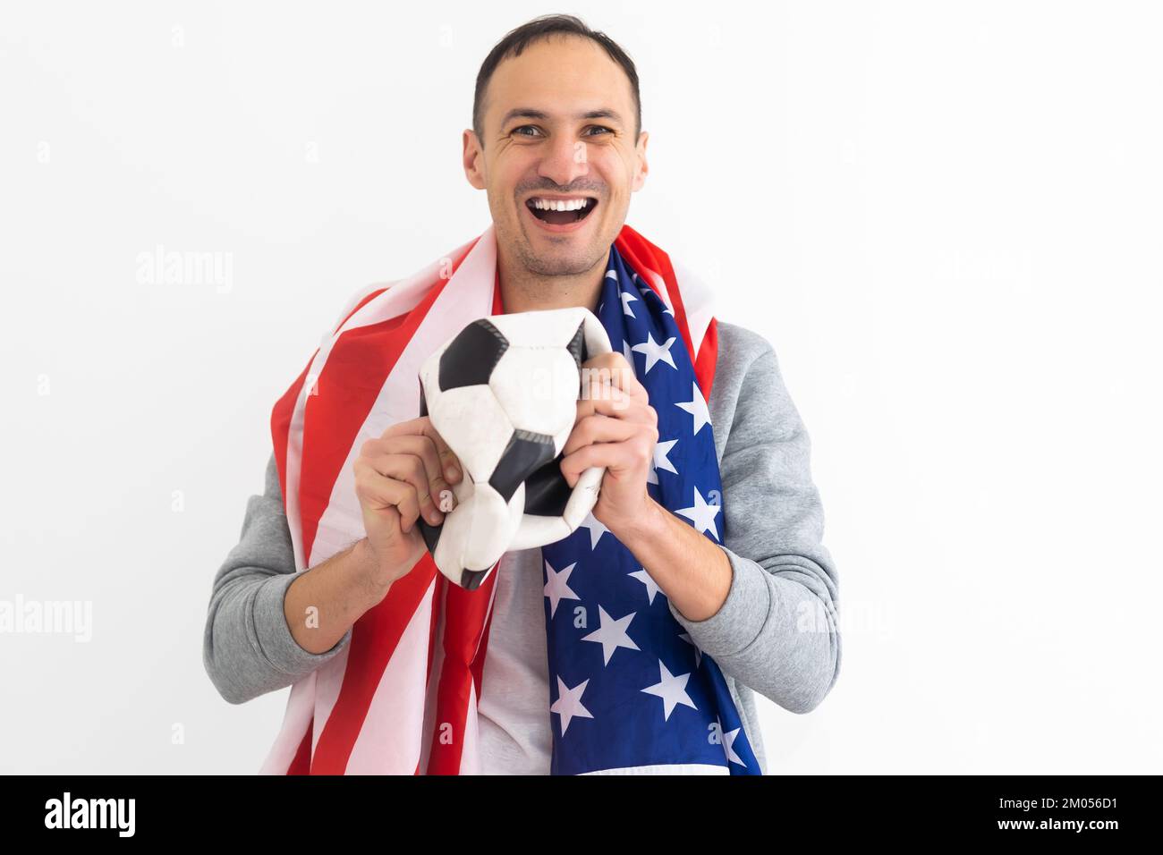 Handsome player man playing soccer holding football ball over ...