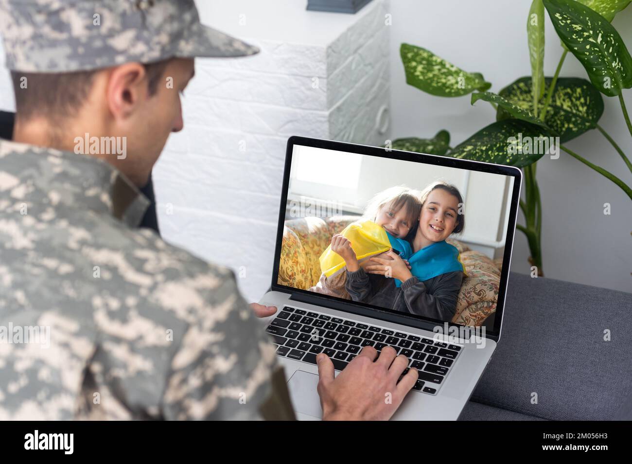 Young soldier in military uniform talking to someone while having video ...