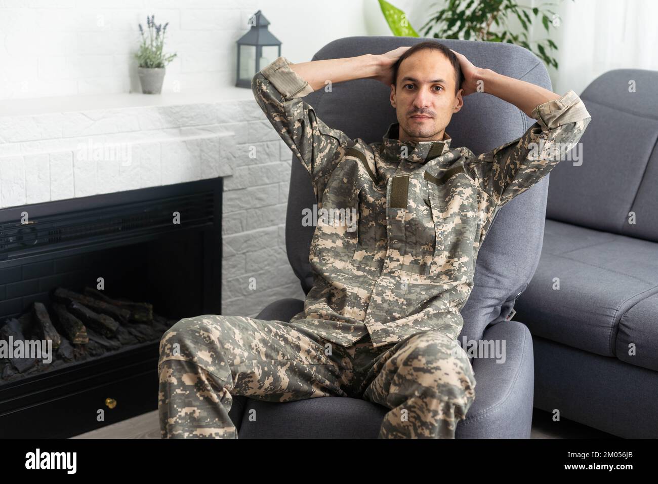 Thoughtful military man staring aside, holding palms by mouth, sitting ...