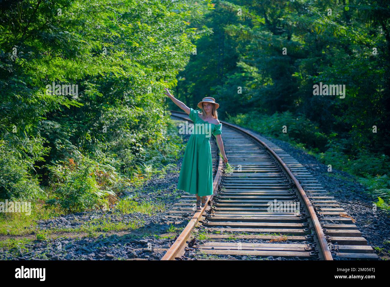 a woman in a green dress walks along the railway Stock Photo - Alamy