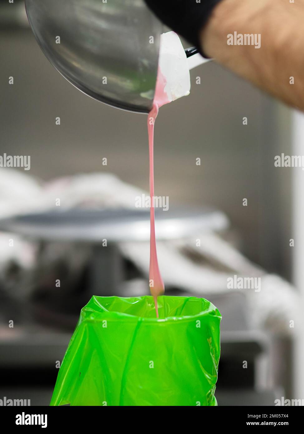 pastry chef filling piping bag filling mixed with edible pink paint for ...