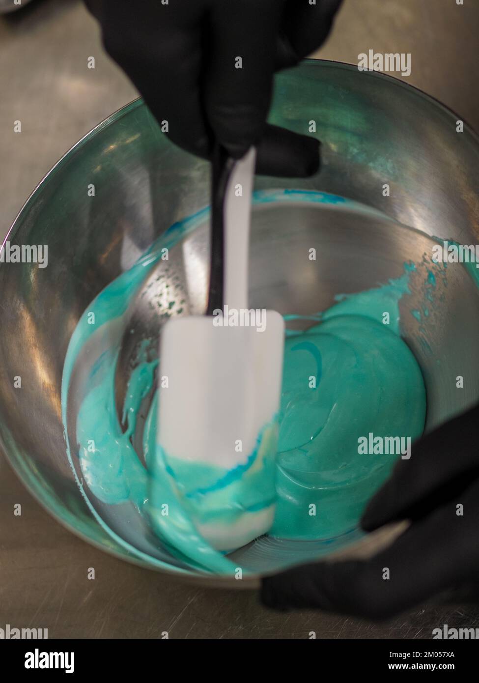 pastry chef stirring piping bag filling mixed with edible turquoise ...