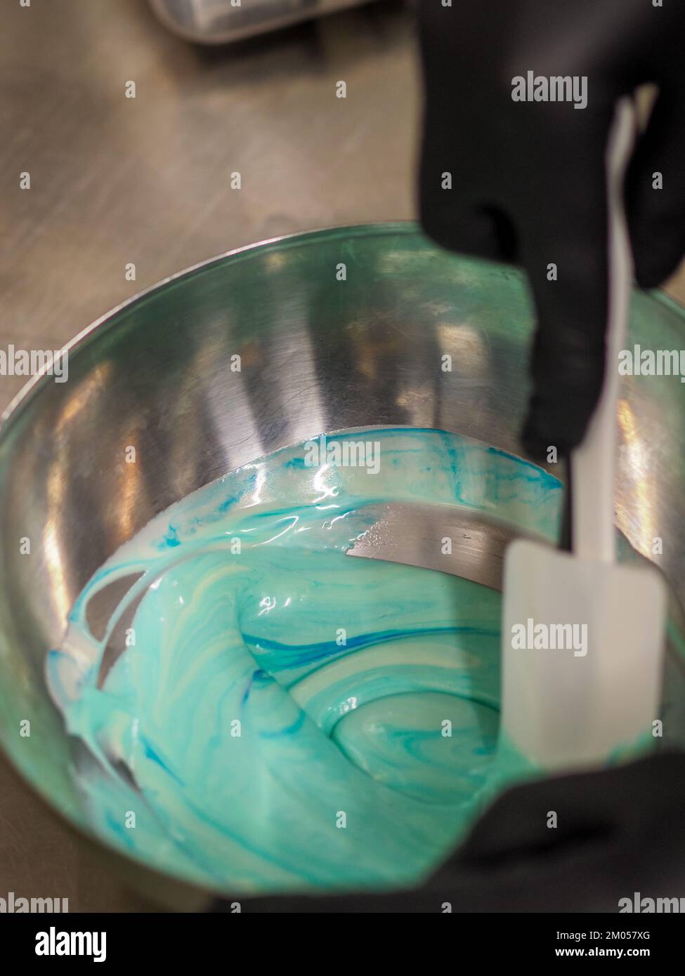 pastry chef stirring piping bag filling mixed with edible turquoise ...