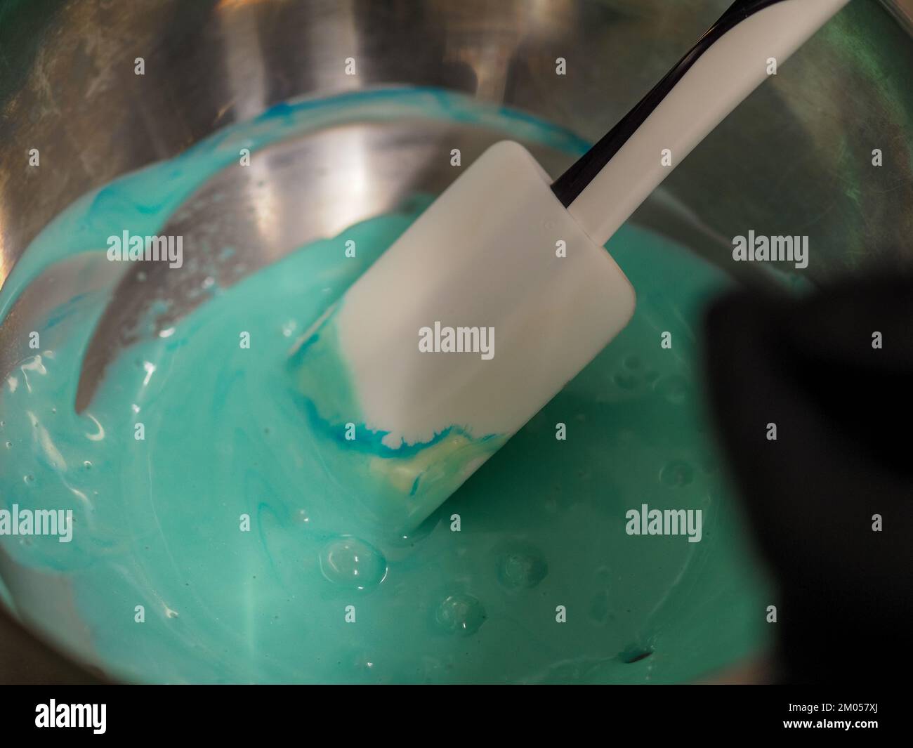 pastry chef stirring piping bag filling mixed with edible turquoise ...