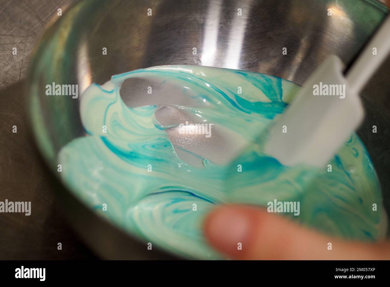 pastry chef stirring piping bag filling mixed with edible turquoise ...