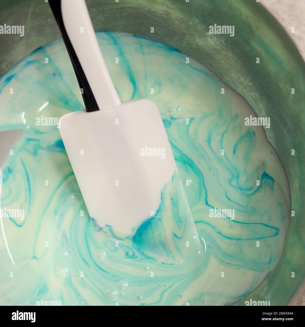 pastry chef stirring piping bag filling mixed with edible turquoise ...