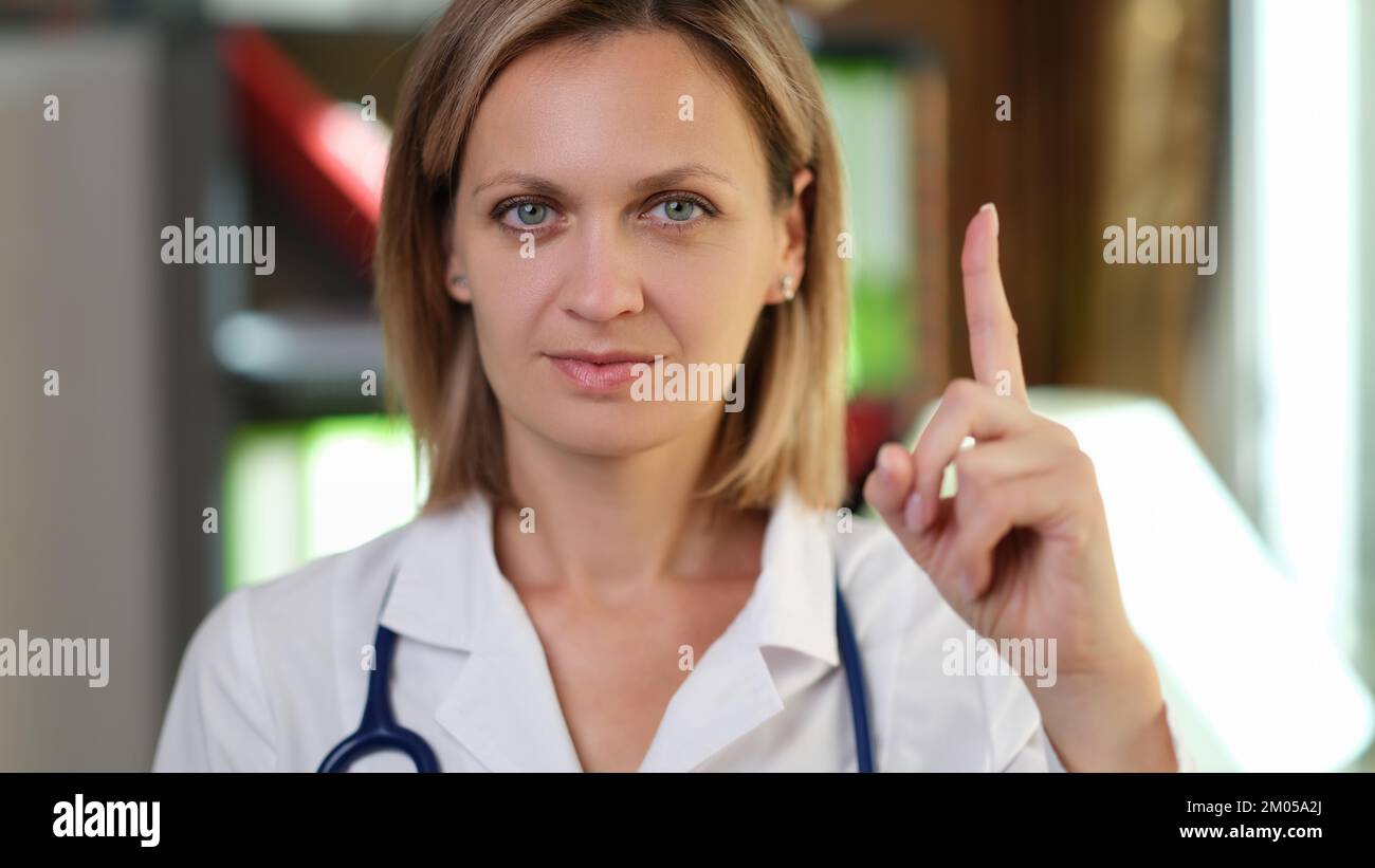 Female doctor pointing her finger up in medical office Stock Photo - Alamy