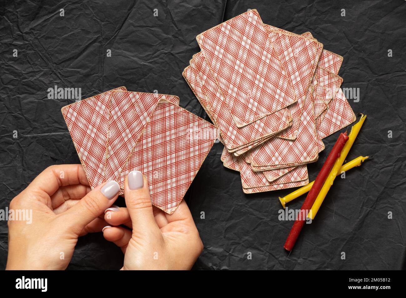 cards in the hands of a fortune teller and candles on the table ...