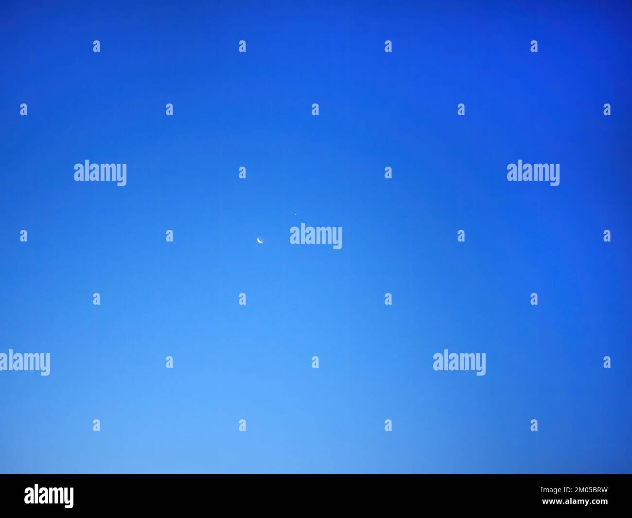 Blue sky with new moon, a crescent moon and star in the bright twilight ...