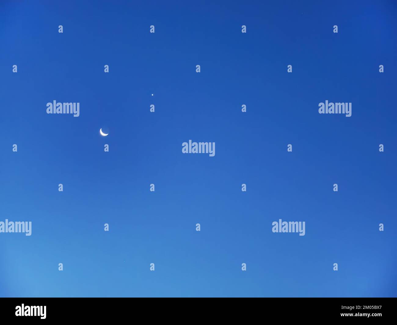 Blue sky with new moon, a crescent moon and star in the bright twilight ...