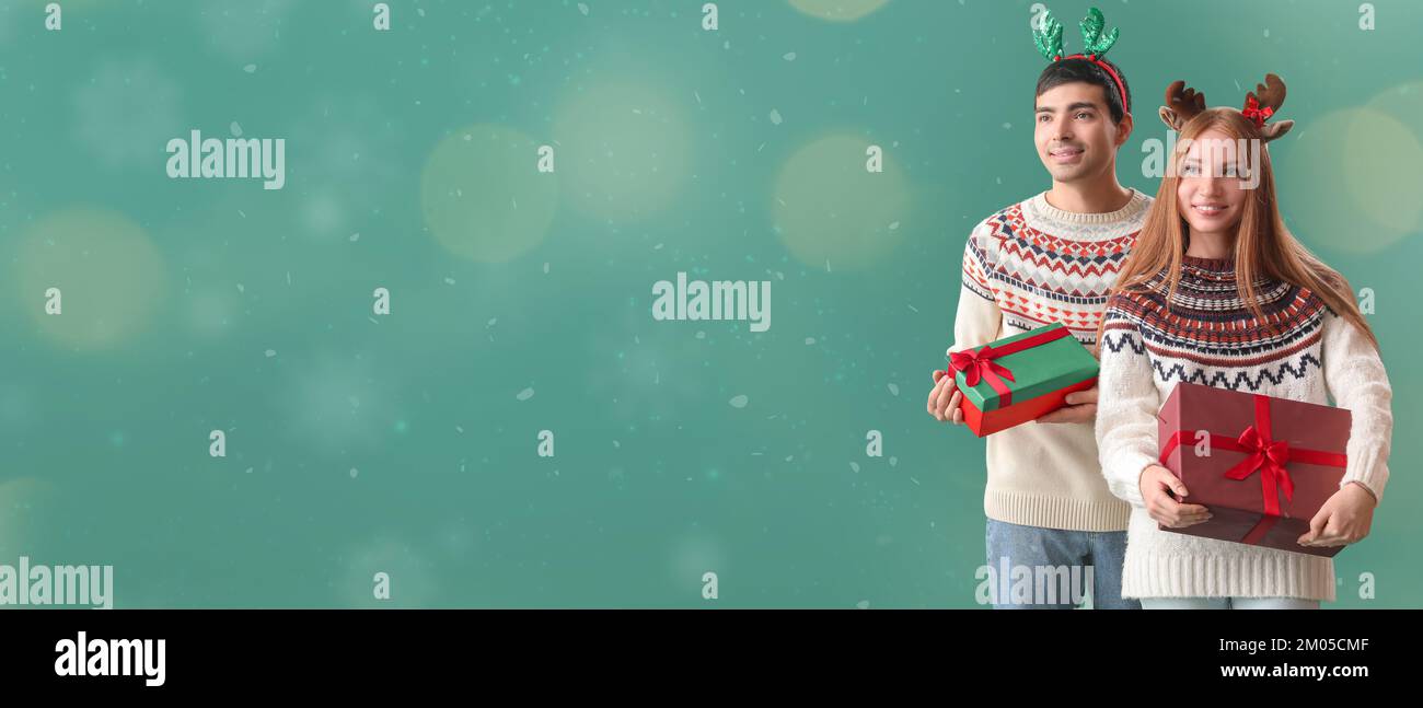 Happy young couple holding Christmas presents on green background with ...